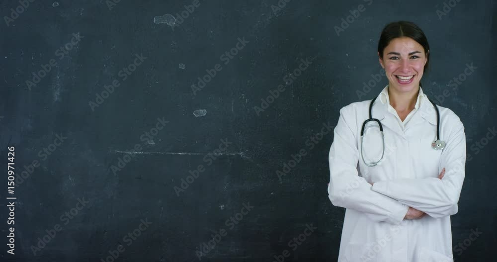 Portrait of a beautiful female doctor (student) stands by a black board ...