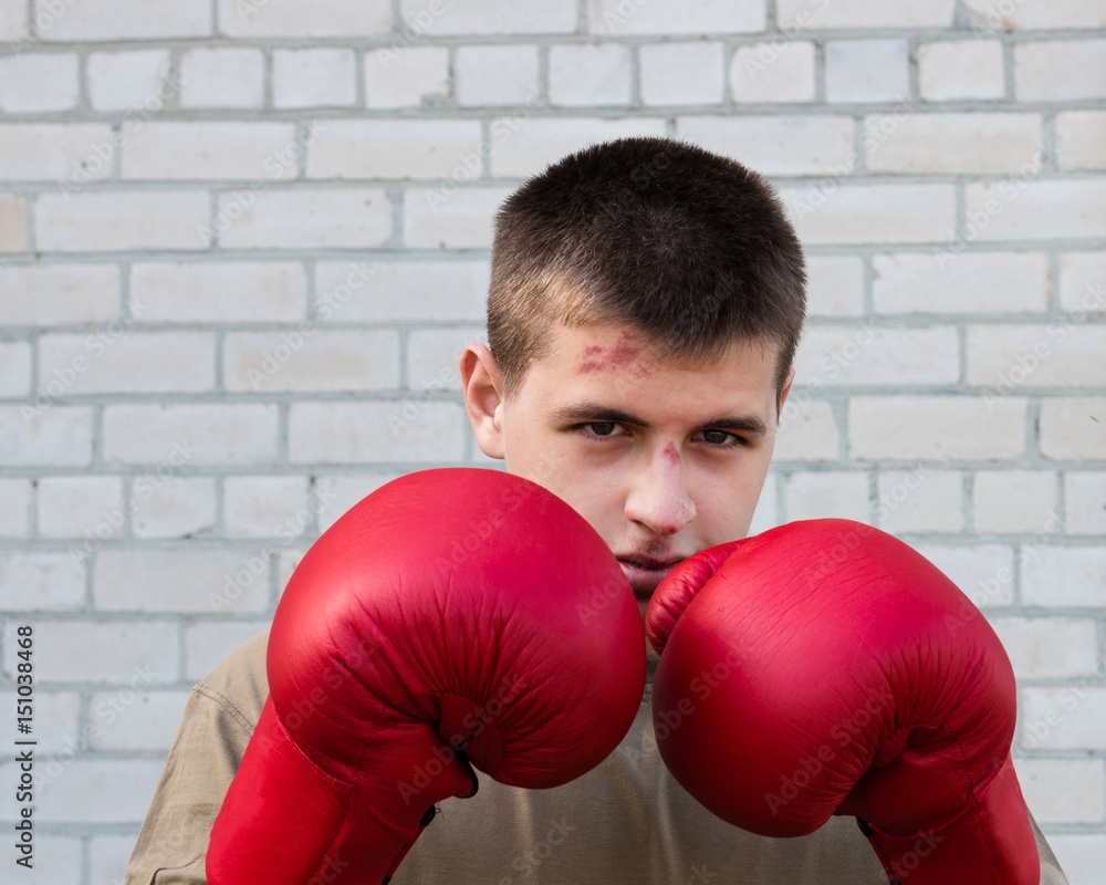 17 year old teenager boy with a battered face and boxing gloves. Boxing ...