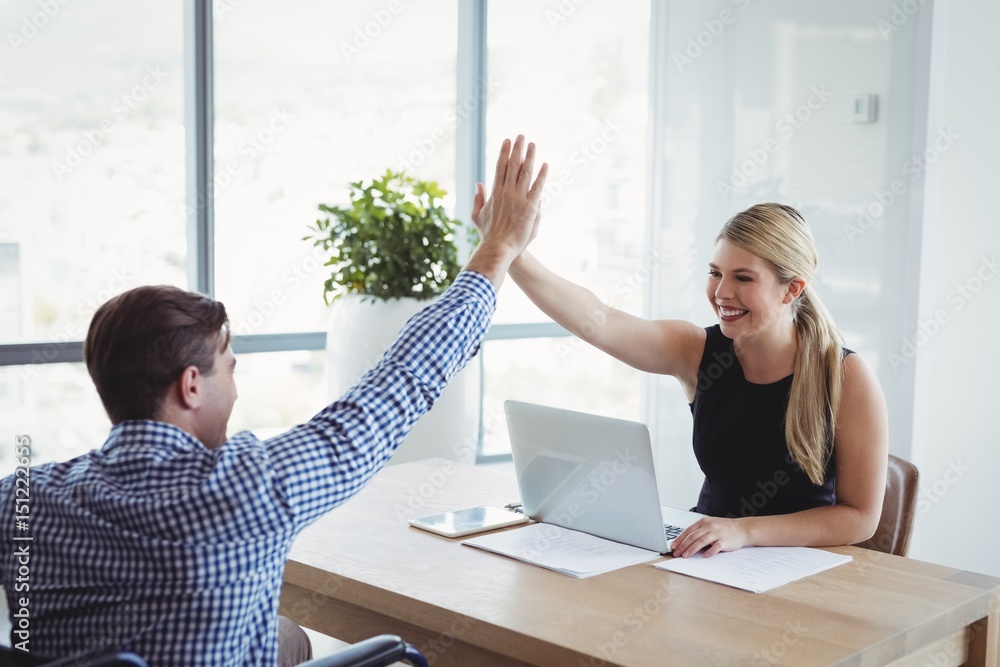 Smiling executives giving high-five to each other at desk Stock Photo ...