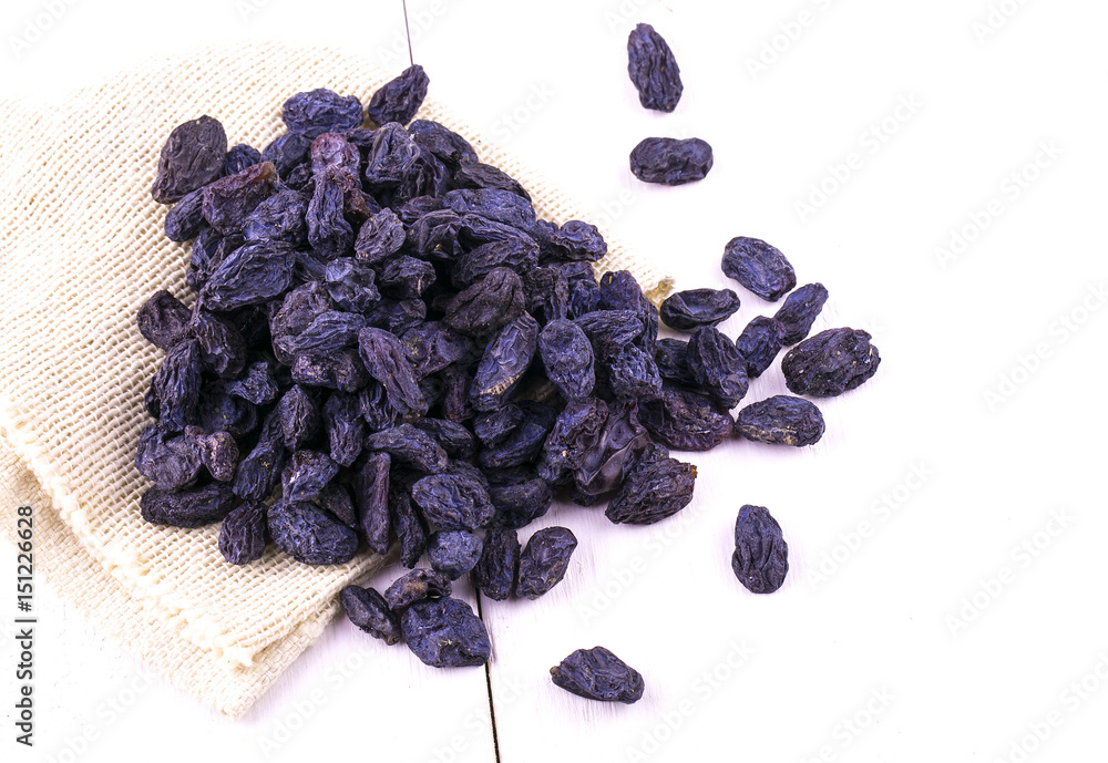 Blue raisins scattered on sackcloth on a white wooden table. Stock ...
