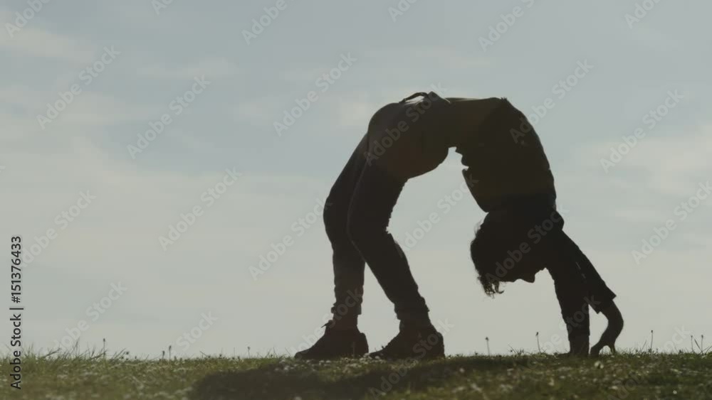 Male silhouette contortionist walking on his hands and feet whilst bent ...