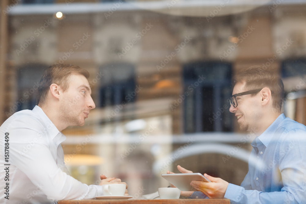Side view portrait of two men meeting in cafe sitting on opposite sides ...