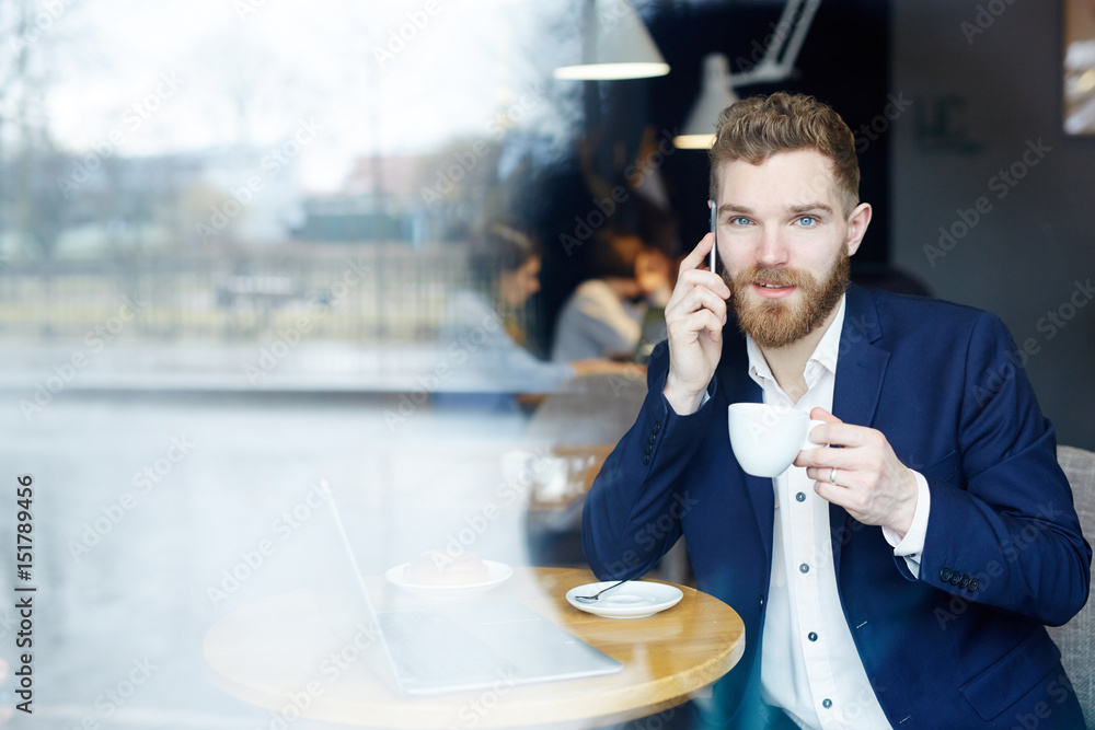 Confident businessman with cup of coffee calling in cafe Stock-Foto ...