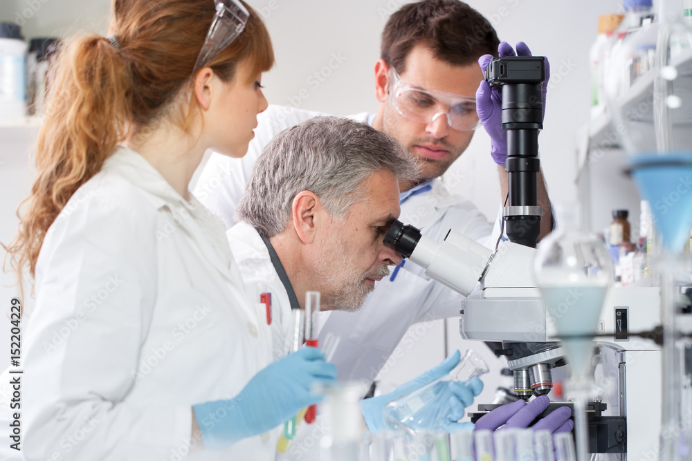 Health care researchers microscoping in life science laboratory. Young ...