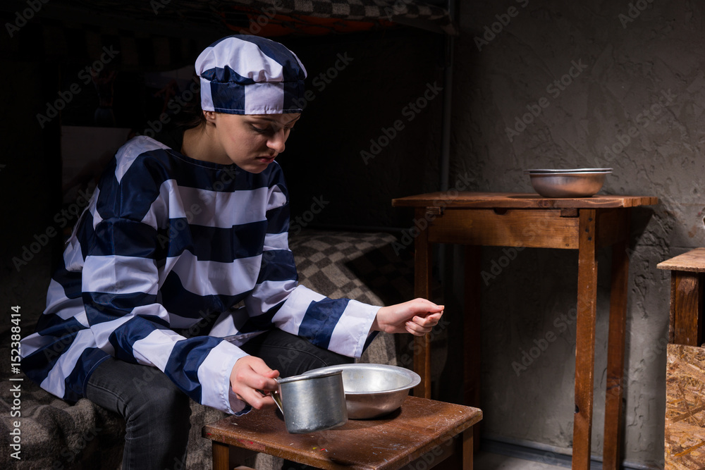 Female prisoner eating from aluminum dishes in a small prison cell ...