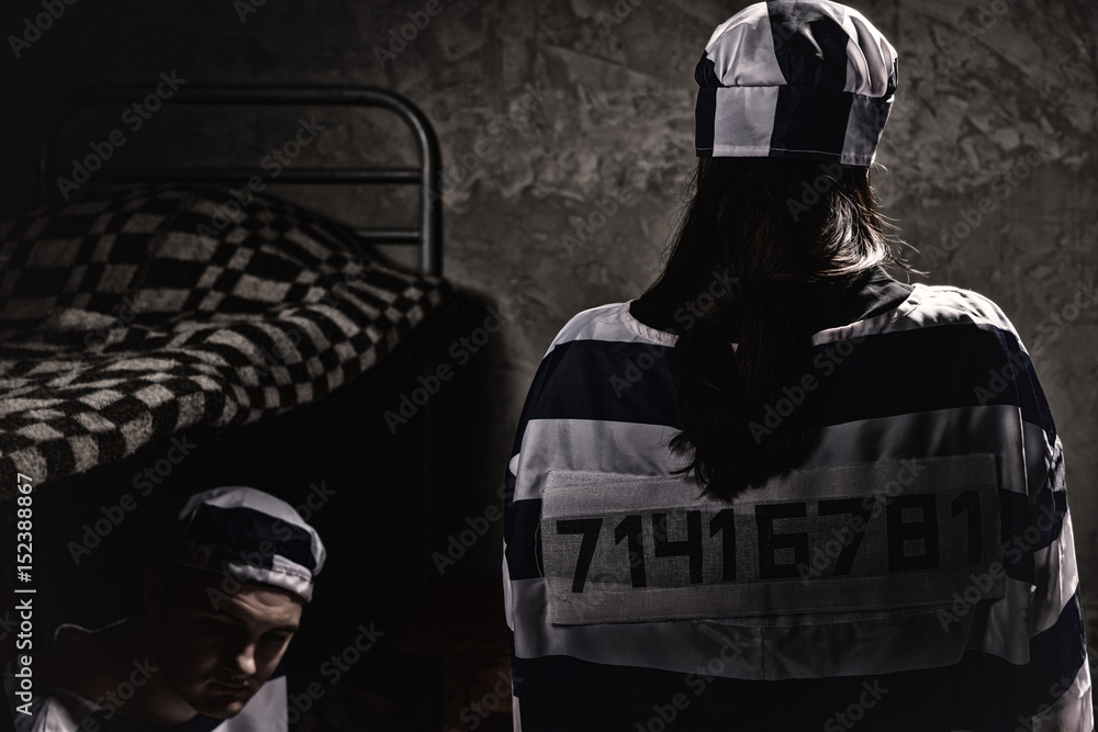 Female prisoner wearing prison uniform with sewed number standing with ...