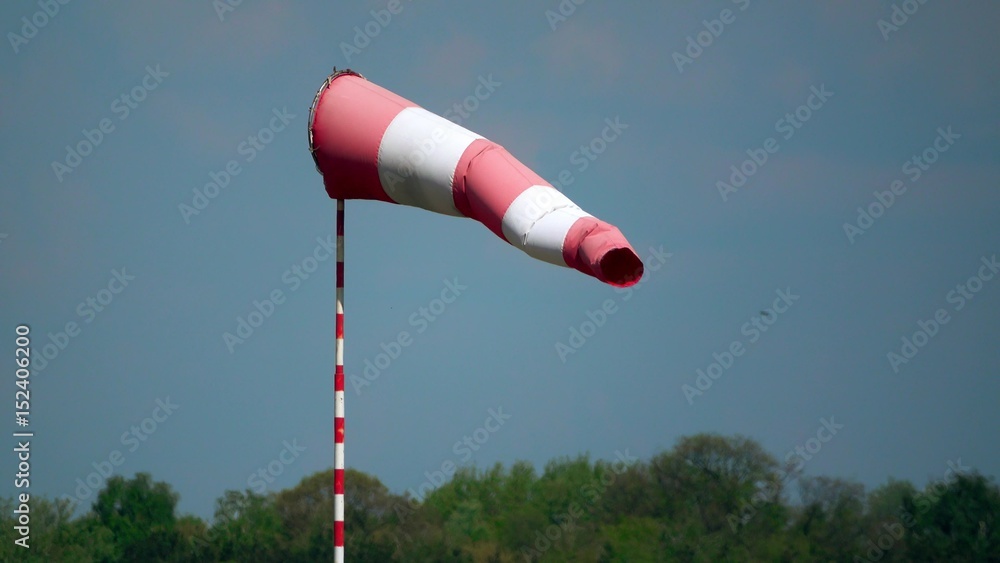 Foto de Waving airport weather vane or striped wind flag telephoto lens ...