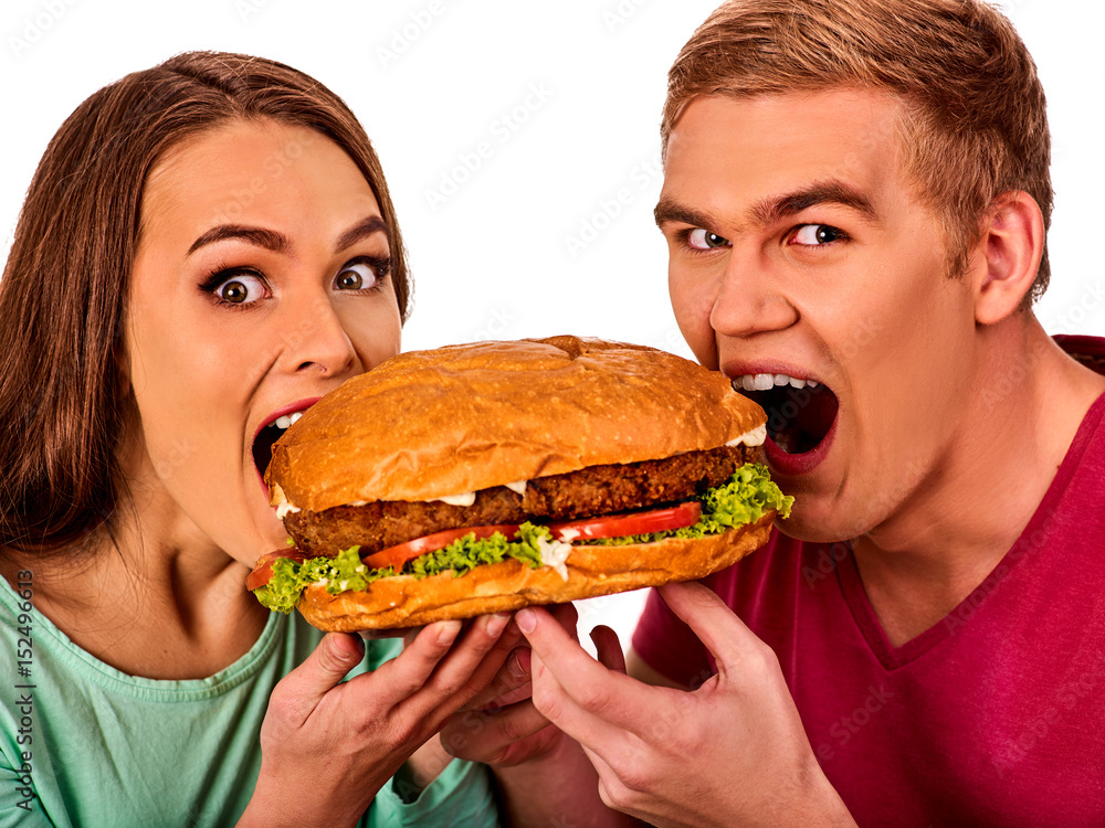 Couple eating fast food. Man and woman treat big hamburger with ham ...