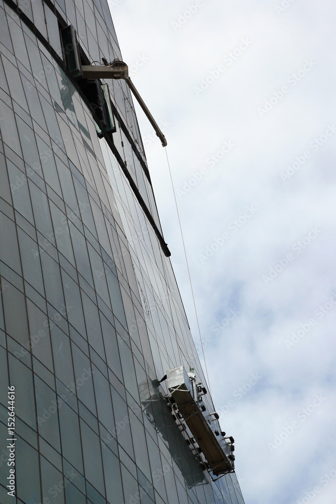 Window washing workers in the platform suspended on rotating arm of the ...