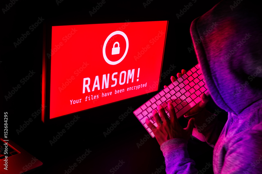 Computer screen with ransomware attack alert in red and a hacker man ...