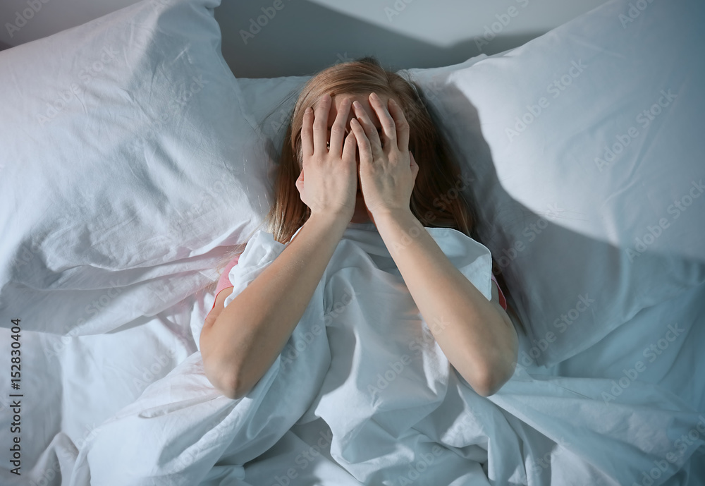 Young scared woman lying in bed at home Stock Photo | Adobe Stock