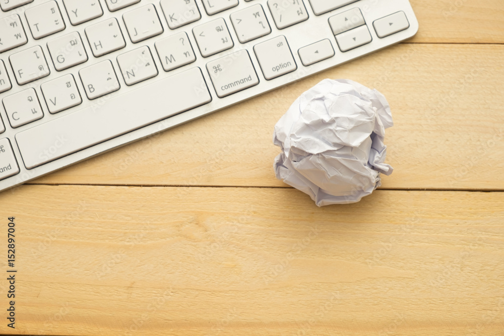 op view. round garbage paper putting beside keyboard on wooden ...