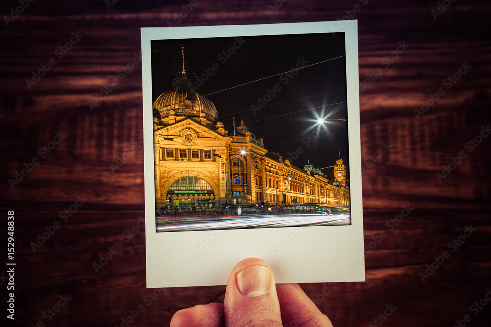 Hand holding polaroid postcard of Flinders Street Station at night ...