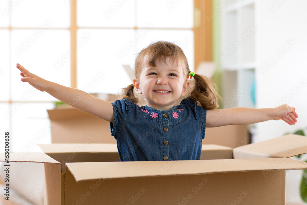 Laughing child girl sitting inside cardboard boxe in her new home Stock ...