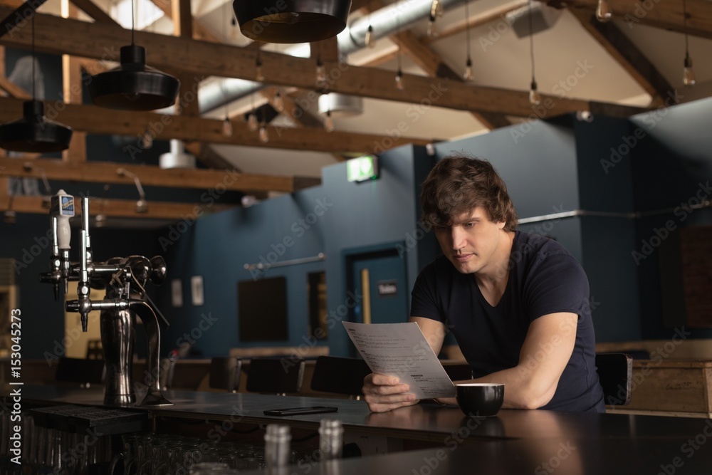 Man looking at menu card while having coffee Stock Photo | Adobe Stock