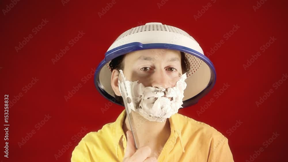 A funny ugly angry crazy man, with a colander on his head, shaving his ...