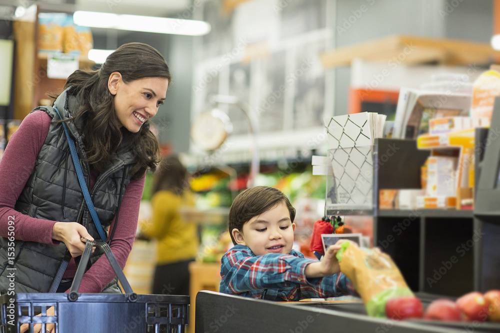 Mother and son keeping food on checkout counter at supermarket Stock ...