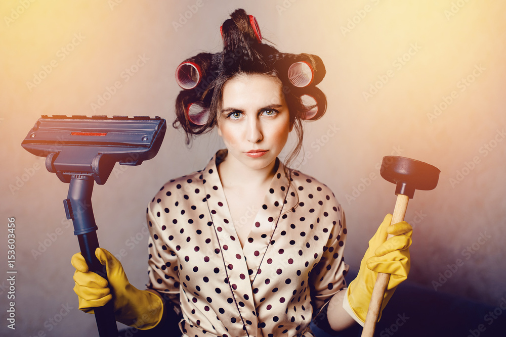 Foto Stock girl with curls on the head of a hair curler holds a plunger ...