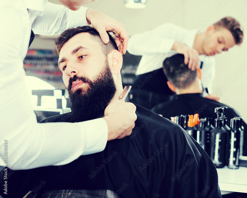 Adult stylist creating shape for beard of client Stock Photo | Adobe Stock