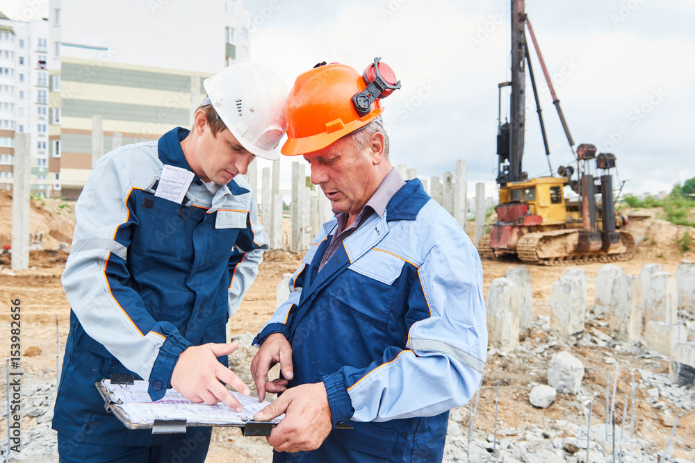 construction workers with project in front of pile driver machine Stock ...