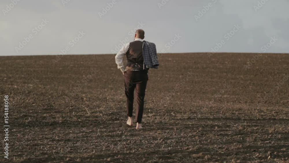 Bearded man in a suit in the field barefoot. Male in a classic costume ...