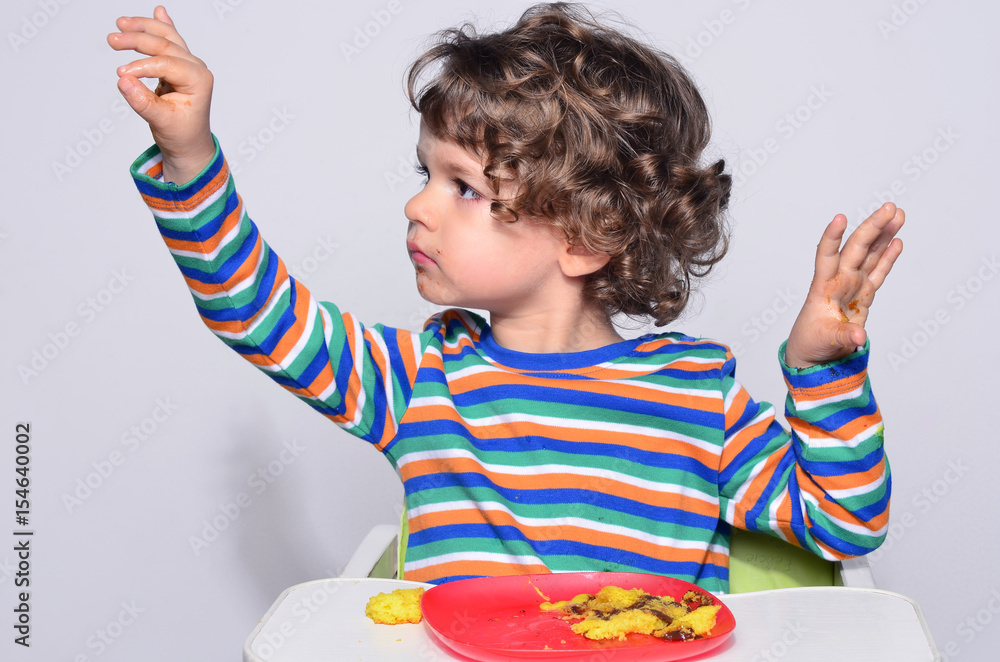 Kid getting messy while eating a chocolate cake. Beautiful curly hair ...
