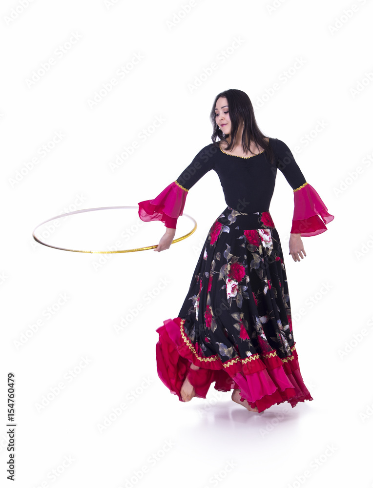 A young,smiling girl in a long skirt dancing with a Hoop. Studio shot ...