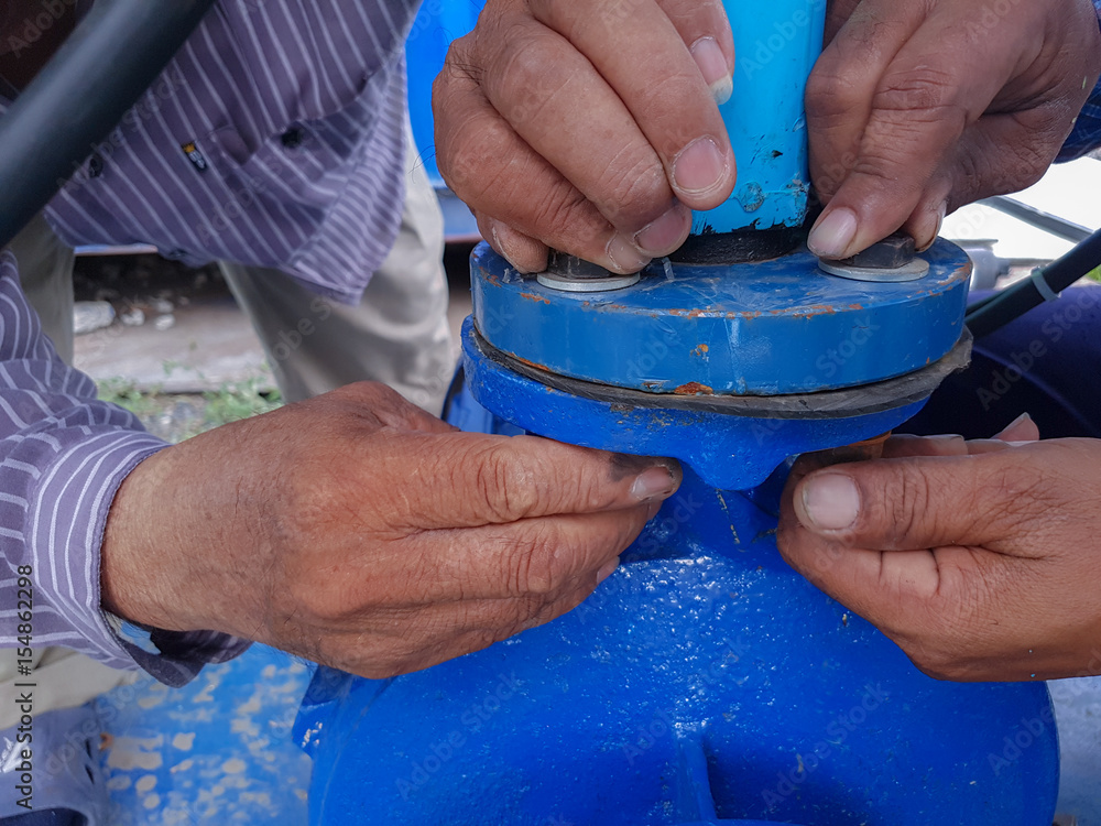Hands of two men who helped assemble the flange bolts of the water pump ...