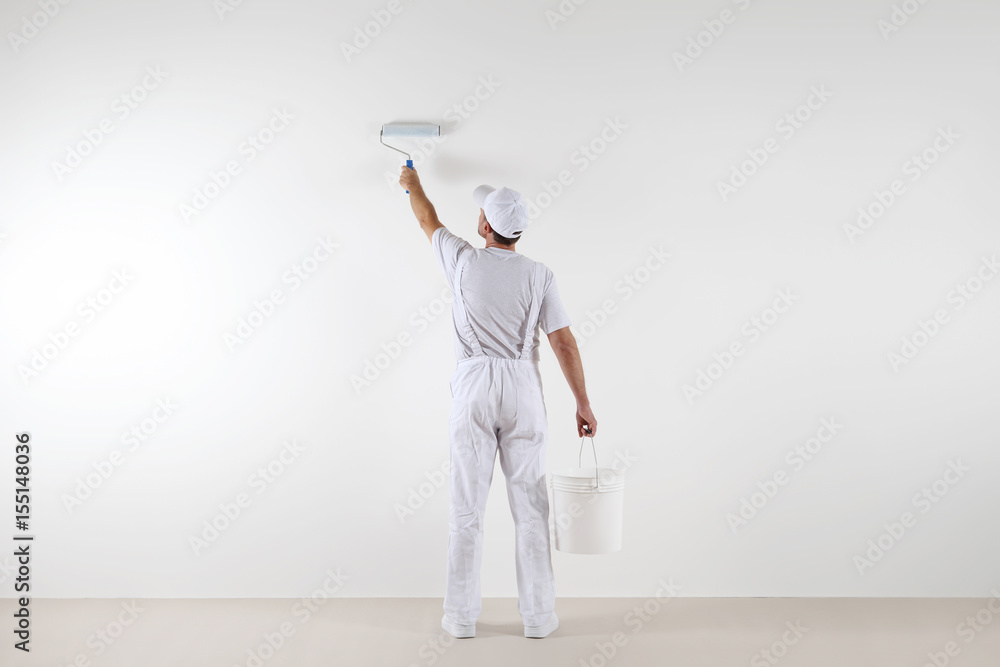 Rear view of painter man painting the wall, with paint roller and ...