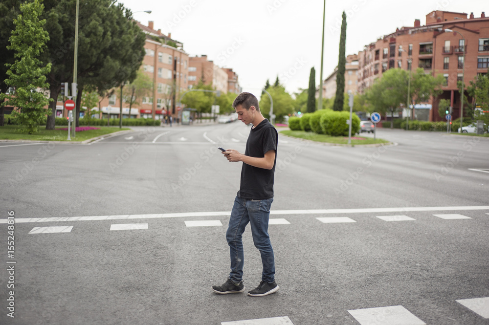 Boy walking by a pedestrian crossing with the phone Stock Photo | Adobe ...