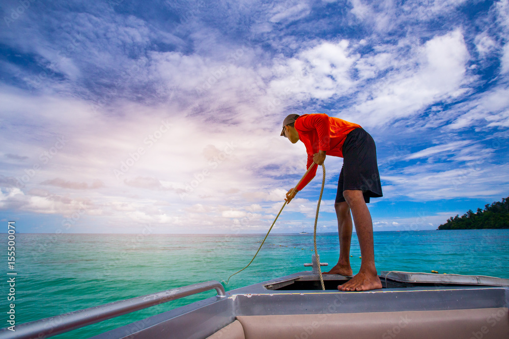Speed boat crew picking up the anchor from the blue and clean ocean at ...