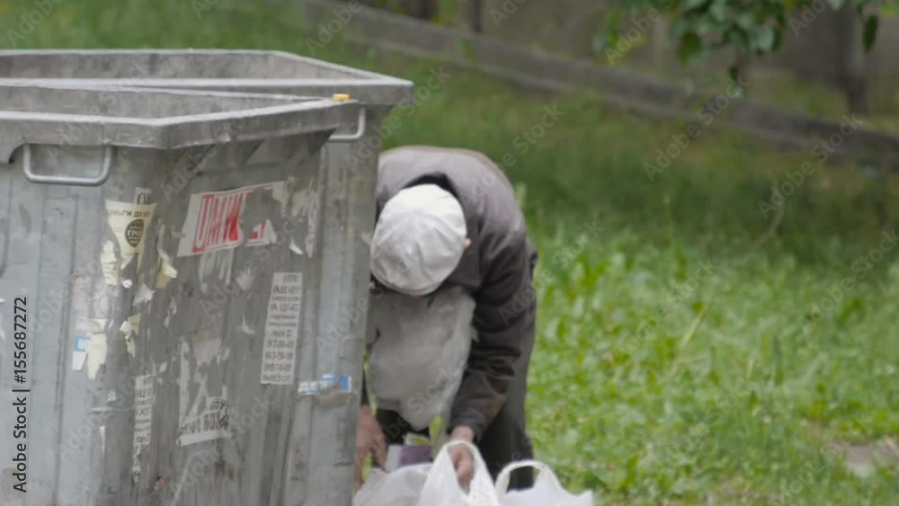 Homeless old man finds а waste in garbage cans and puts them the ...