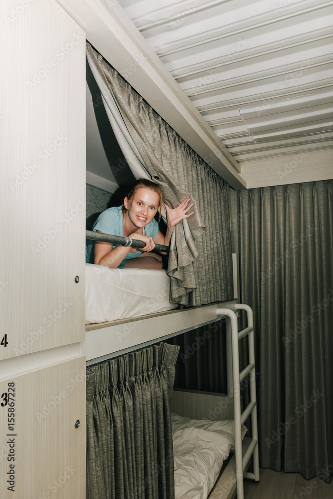 Girl lying in a stylish hostel bedroom. Young woman sitting on second ...