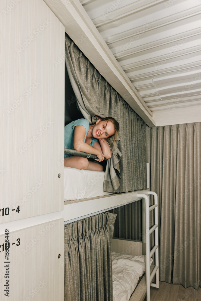 Girl lying in a stylish hostel bedroom. Young woman sitting on second ...