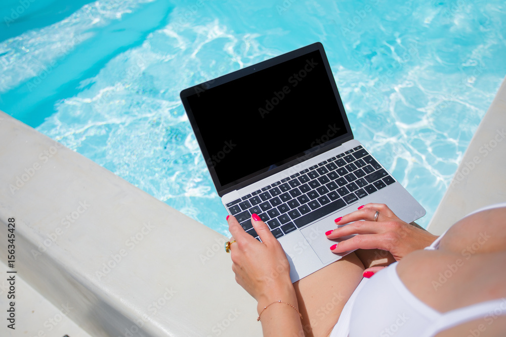Girl wearing bikini working with laptop by the pool Stock Photo | Adobe ...