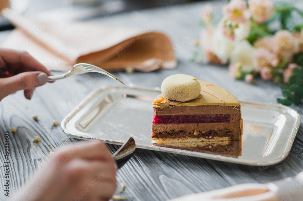 Hands going to eat dessert, yellow mousse cake with almond dacquoise ...