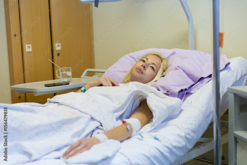 Bedridden female patient lying in hospital bed, recovering after ...