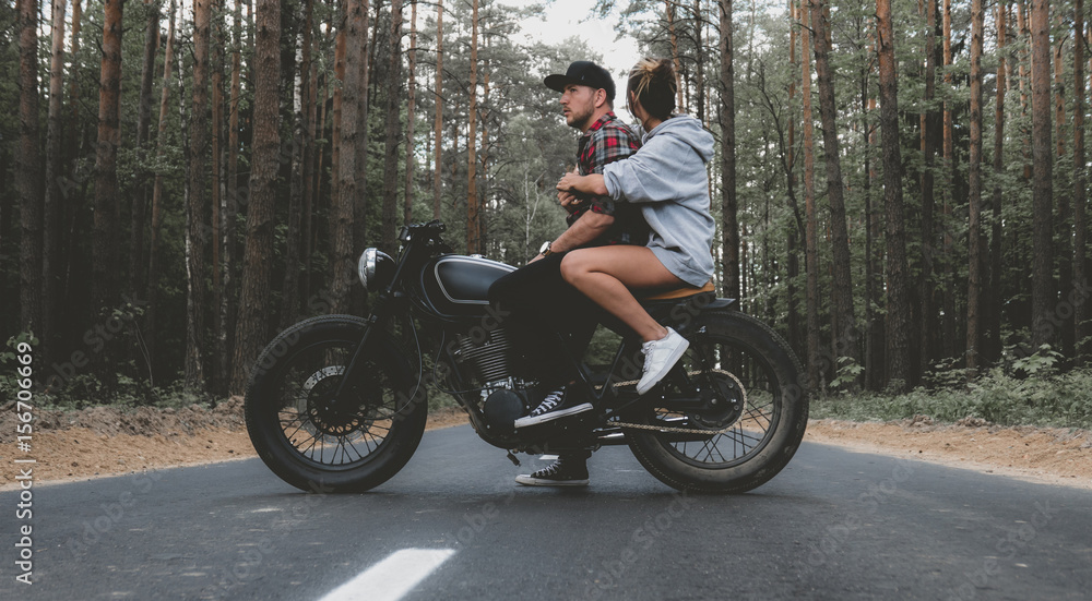 Young Caucasian couple on a motorcycle on the forest road. Love ...