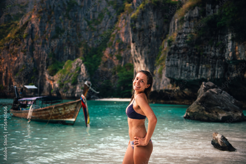 Young tan model on the Maya beach posing wearing bikini with clear water and mountain background ...