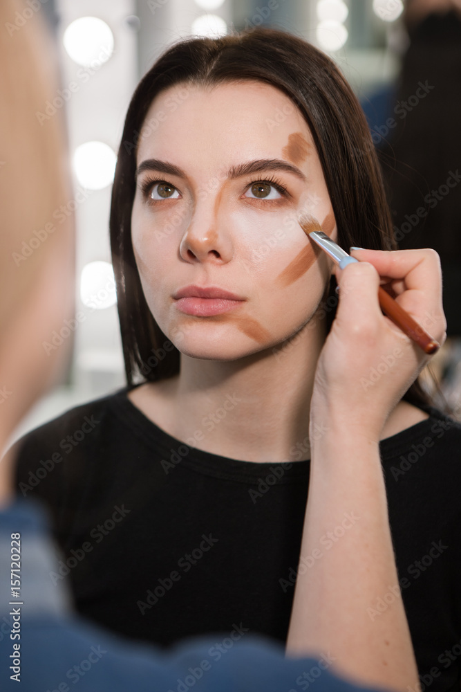 Beautician making contouring on female face. Makeup artist is applying ...