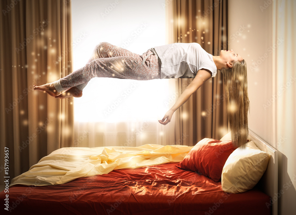 Sleep paralysis concept. Young woman levitating over bed Stock Photo ...