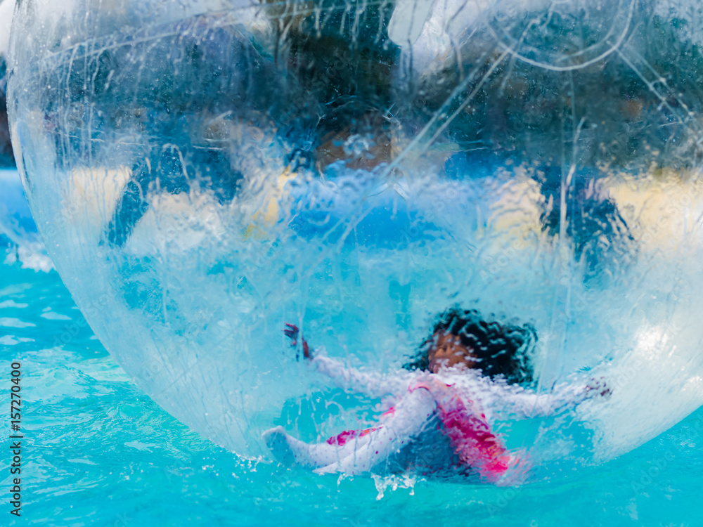 Cute girl in inflatable bubble at water amusement park. Children ...