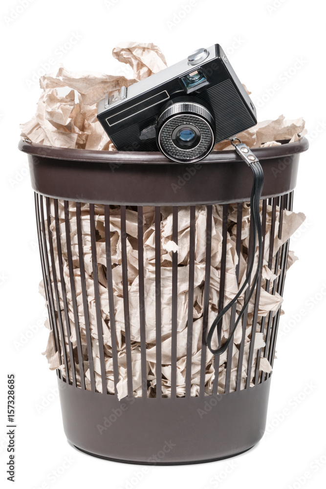 Old film camera in a trash bin full of toilet paper, isolated on a ...