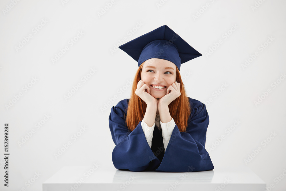 Happy dreamy girl graduate thinking dreaming smiling sitting over white ...