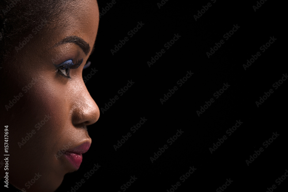 Side view portrait of dark skinned model on a black background. Close ...