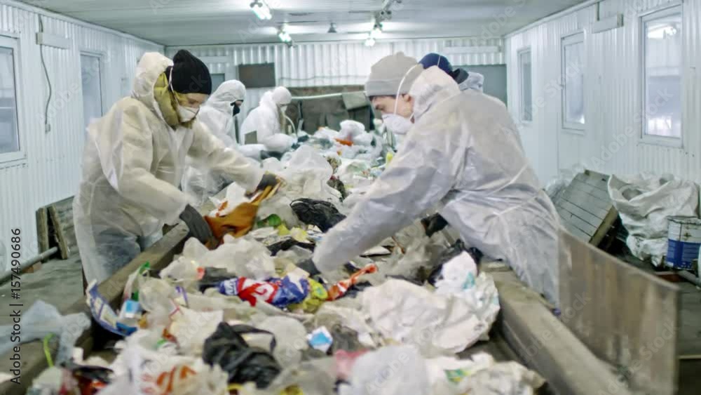 Pan of workers of garbage recycling factory sorting waste lying on ...