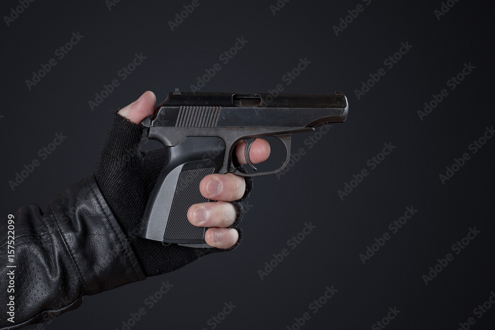 Gangster with a gun in his hand and a leather jacket on a dark ...