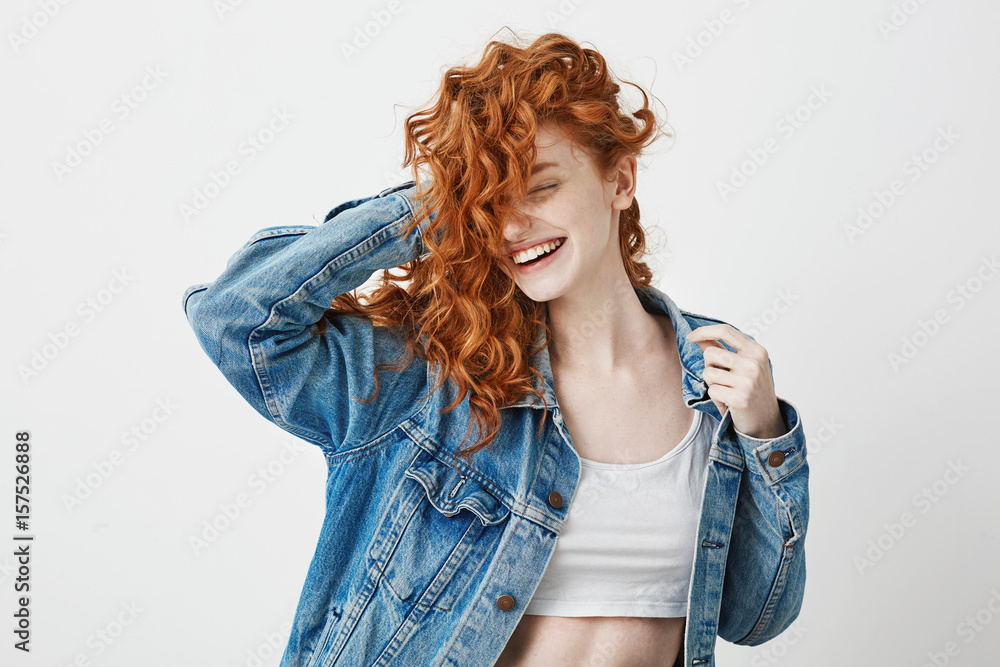 Poster Happy beautiful girl smiling with closed eyes touching her red curly hair over white ...
