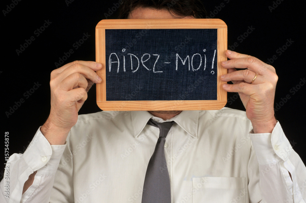 Homme tenant une ardoise devant son visage avec aidez-moi écrit dessus ...