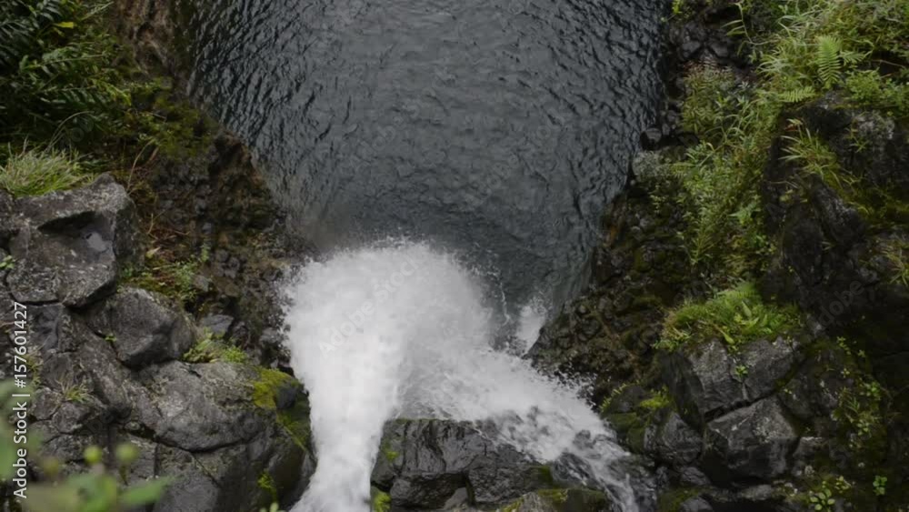 Looking down from the top of a waterfall, camera tilts up to see the ...